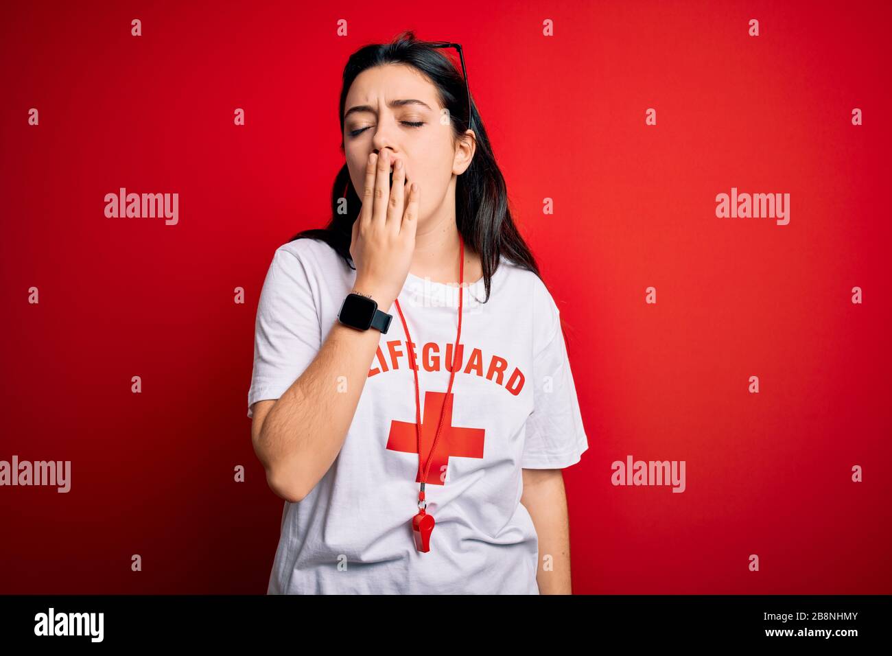 Young lifeguard woman wearing secury guard equipent over red background ...