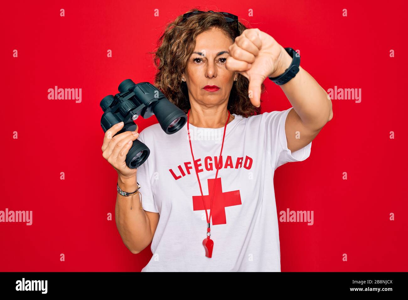 Middle age senior summer lifeguard woman looking through binoculars ...