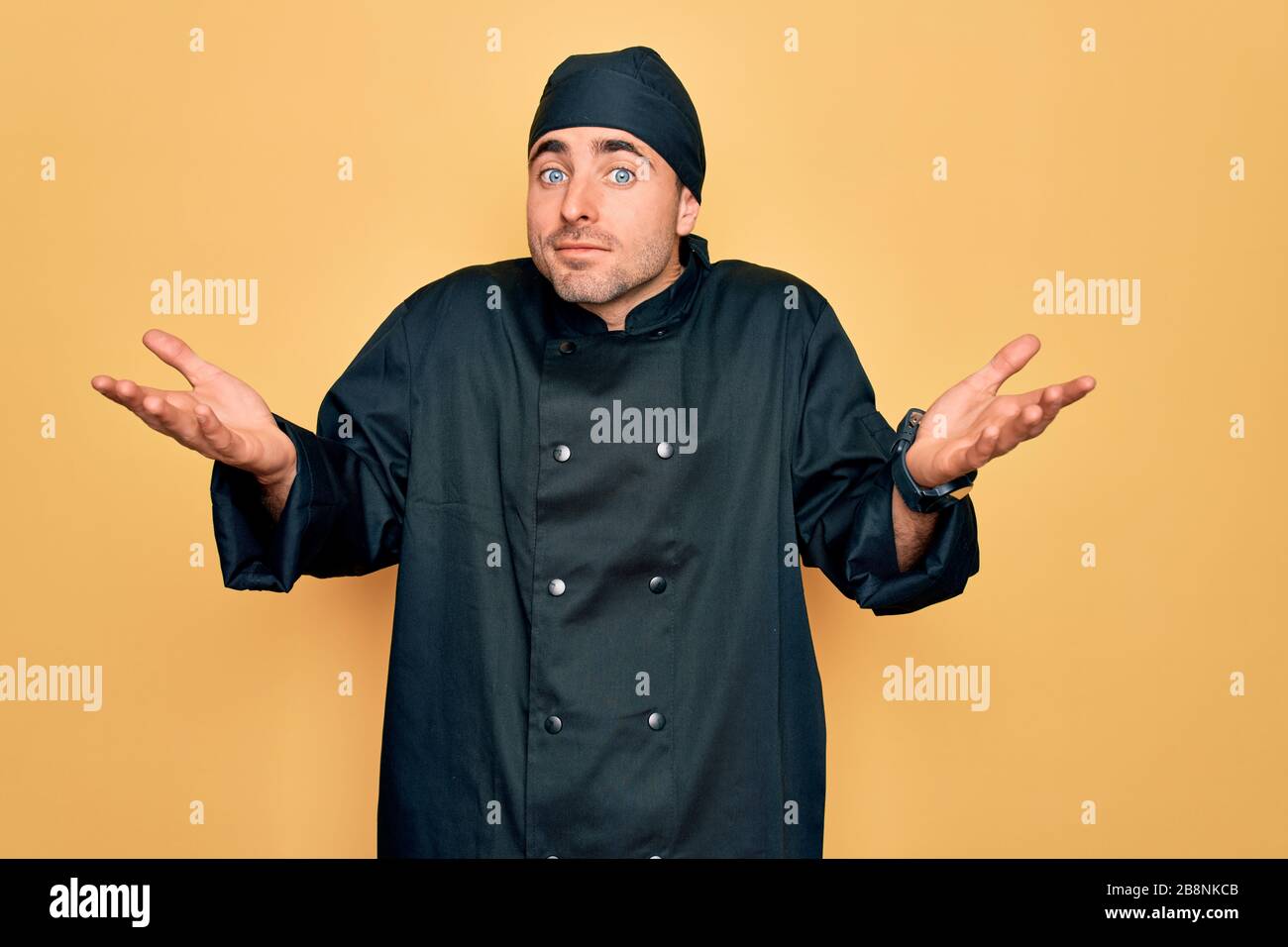 Young handsome cooker man with blue eyes wearing uniform and hat over ...