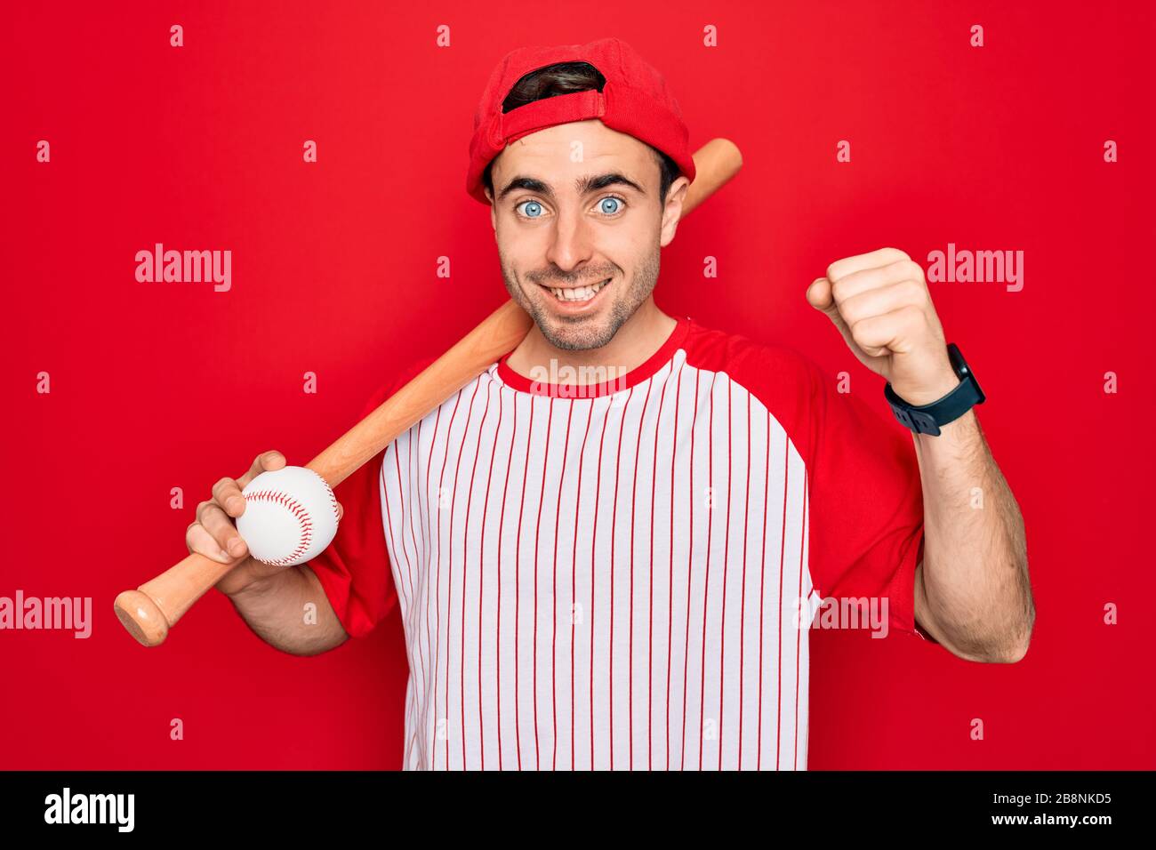 Young handsome sporty man with blue eyes playing baseball wearing cap ...