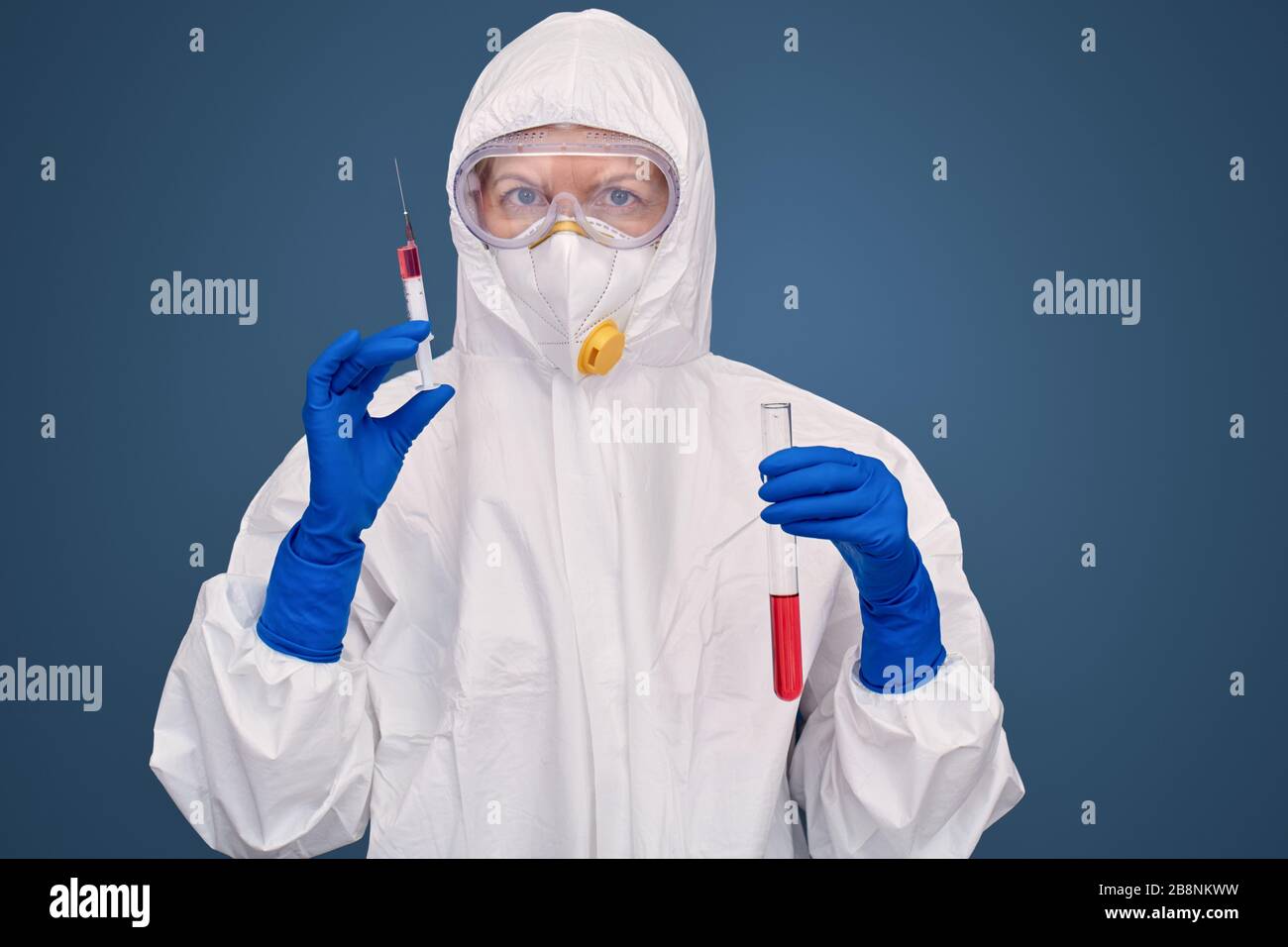 Woman doctor in white hazmat suit holding syringe and test tube Stock ...