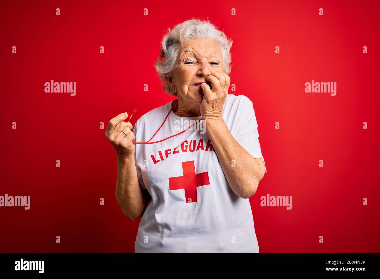Senior beautiful grey-haired lifeguard woman wearing t-shirt with red ...