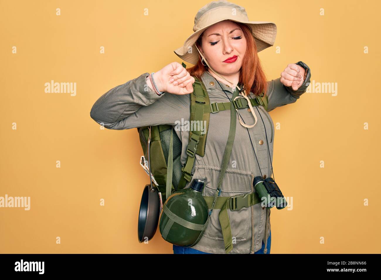 Young redhead backpacker woman hiking wearing backpack and hat over ...