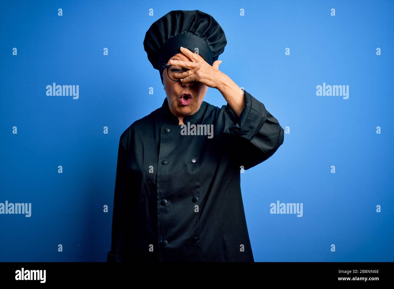 Senior beautiful grey-haired chef woman wearing cooker uniform and hat ...