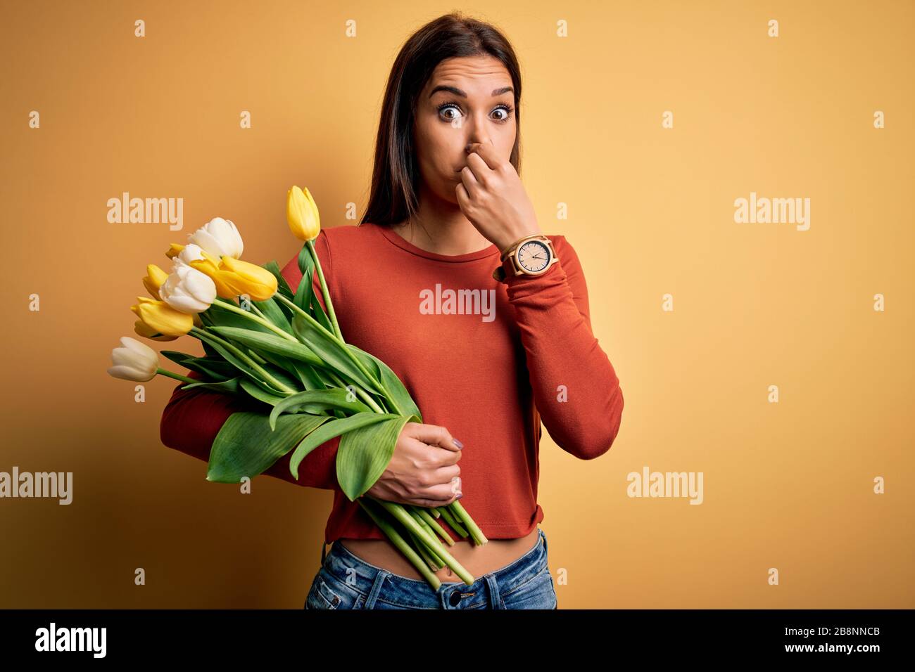 Young beautiful brunette woman holding bouquet of tulips flowers over ...