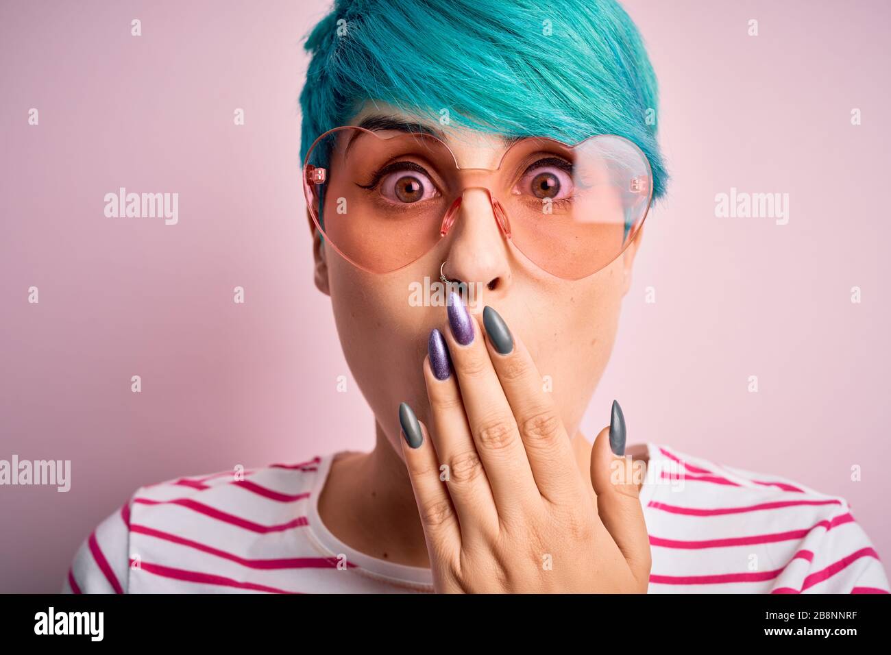 Young beautiful woman with blue fashion hair wearing fanny glasses with ...