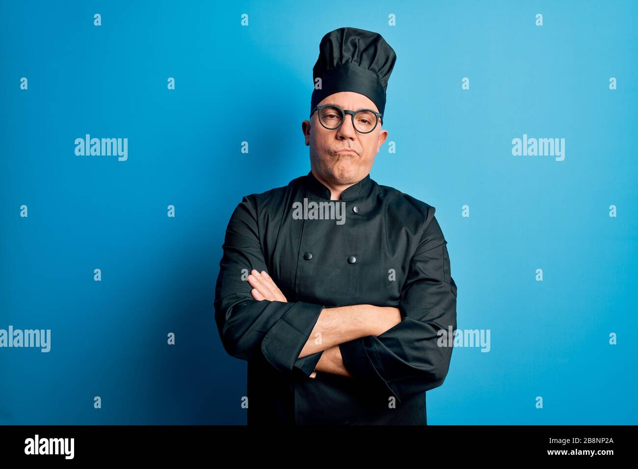 Middle age handsome grey-haired chef man wearing cooker uniform and hat ...