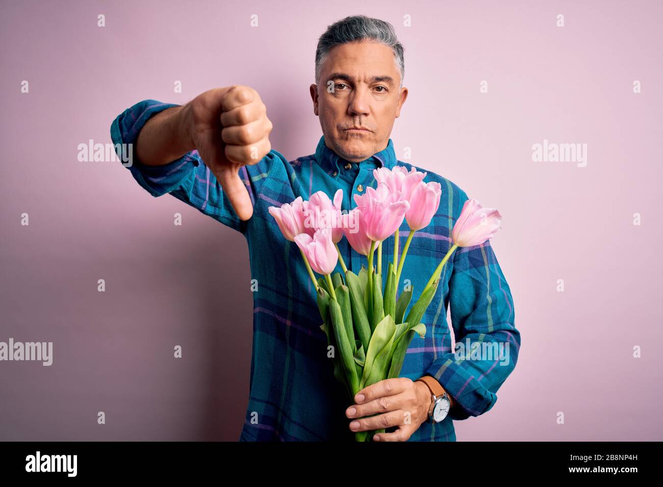 Middle age grey-haired man holding natural bouquet of pink tulips over ...