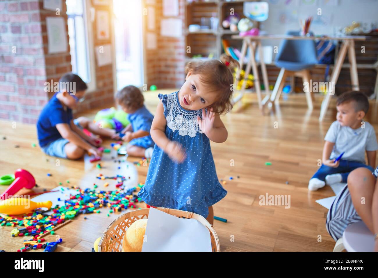 Adorable group of toddlers playing around lots of toys at kindergarten ...