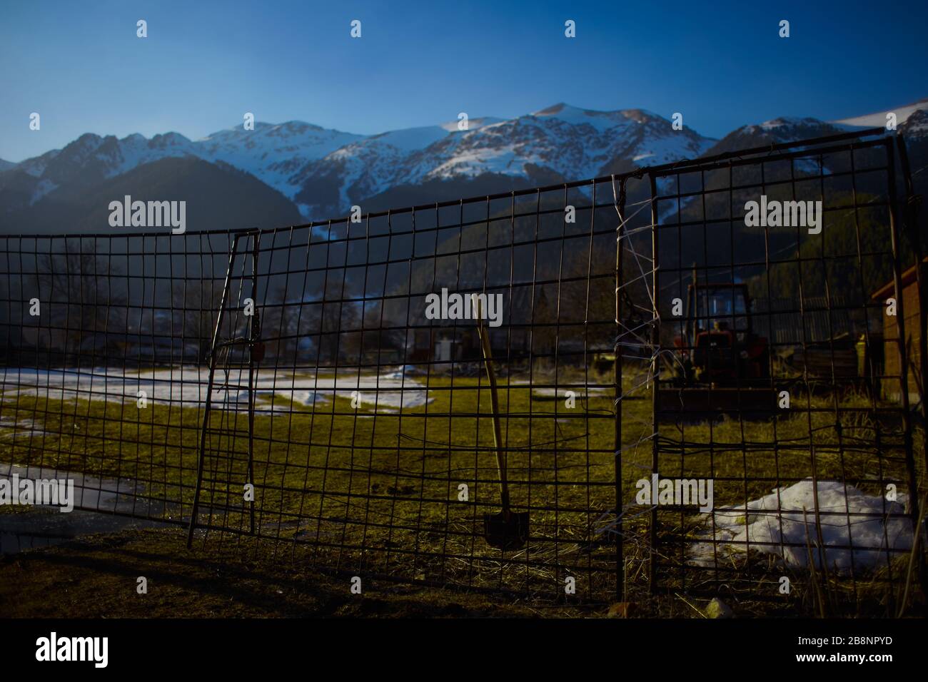 closed mountain border, snow melts, lock on the fence, green grass ...