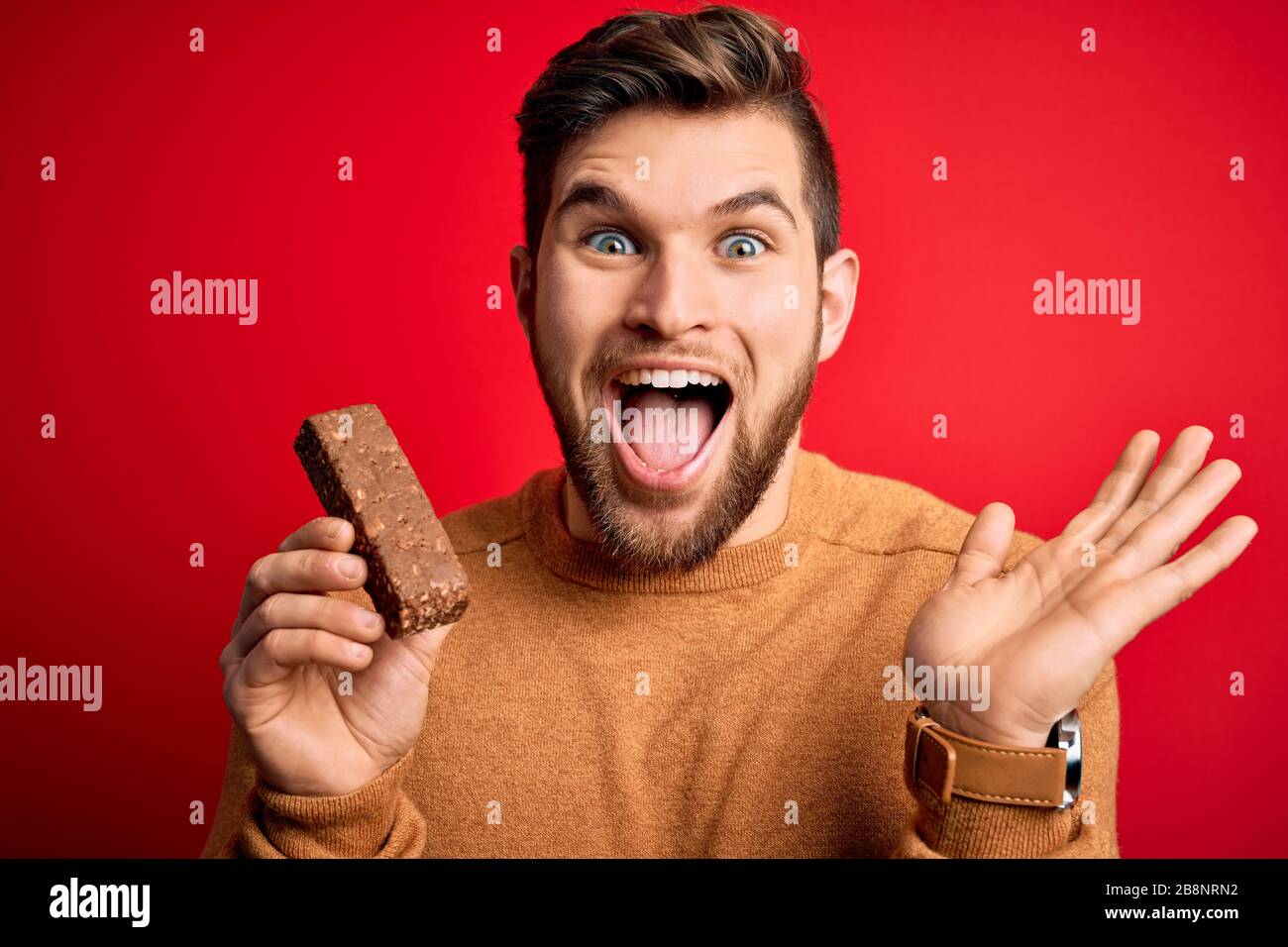 Young blond man with beard and blue eyes eating healthy chocolate ...