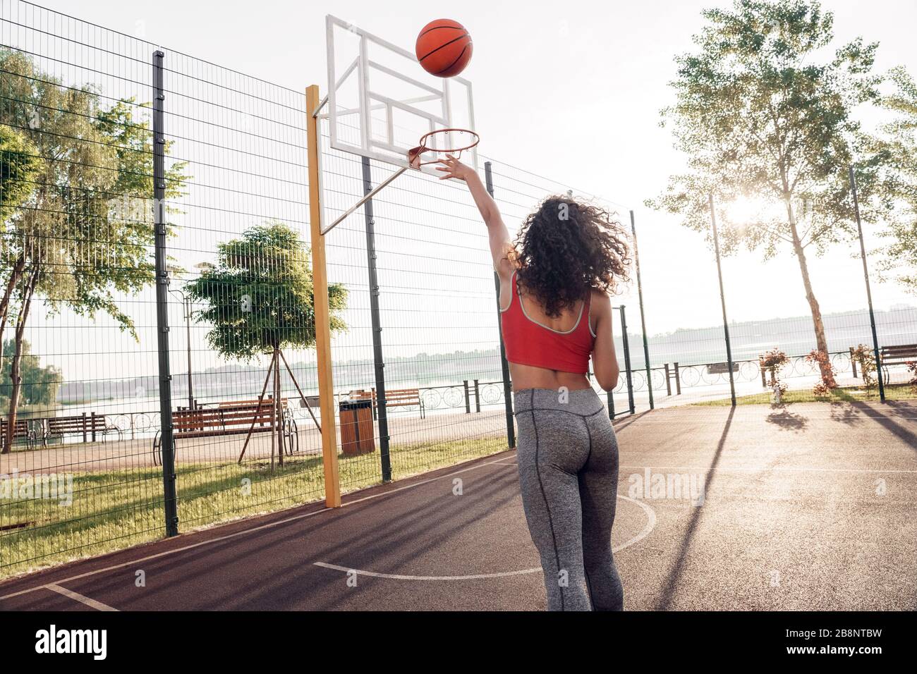 Basketball Player. Woman standing throwing ball to basket on court back ...