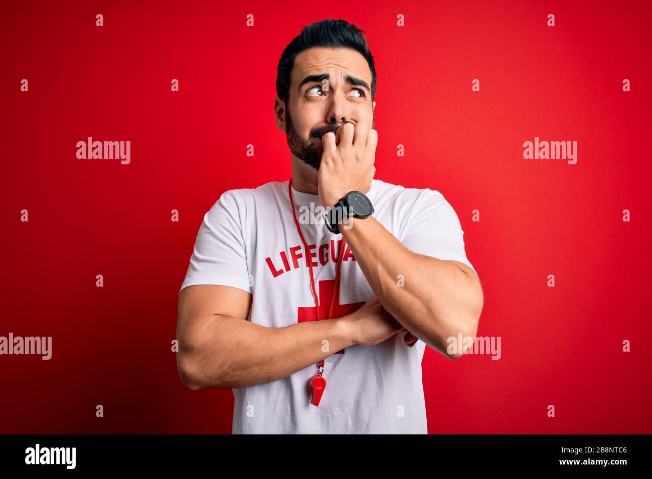 Young handsome lifeguard man with beard wearing whistle over isolated ...