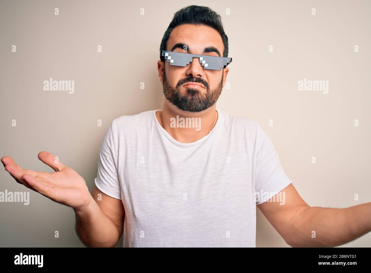 Young handsome man with beard wearing funny thug life sunglasses over ...