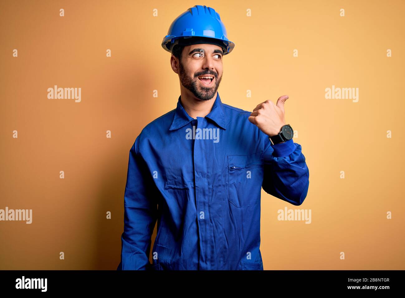 Mechanic man with beard wearing blue uniform and safety helmet over ...