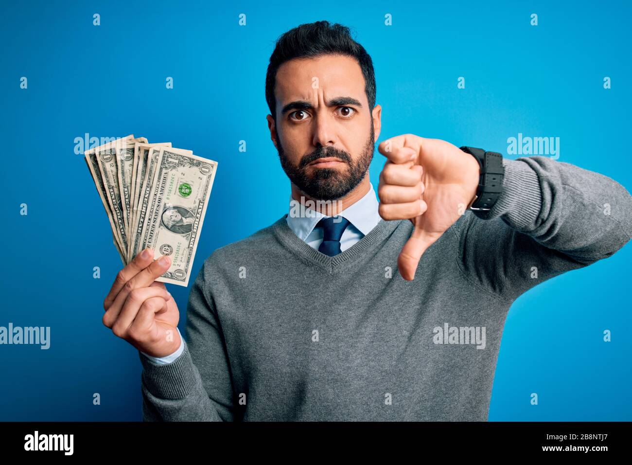 Young handsome man with beard holding bunch of dollars banknotes over ...