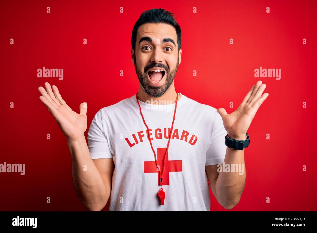 Young handsome lifeguard man with beard wearing whistle over isolated ...