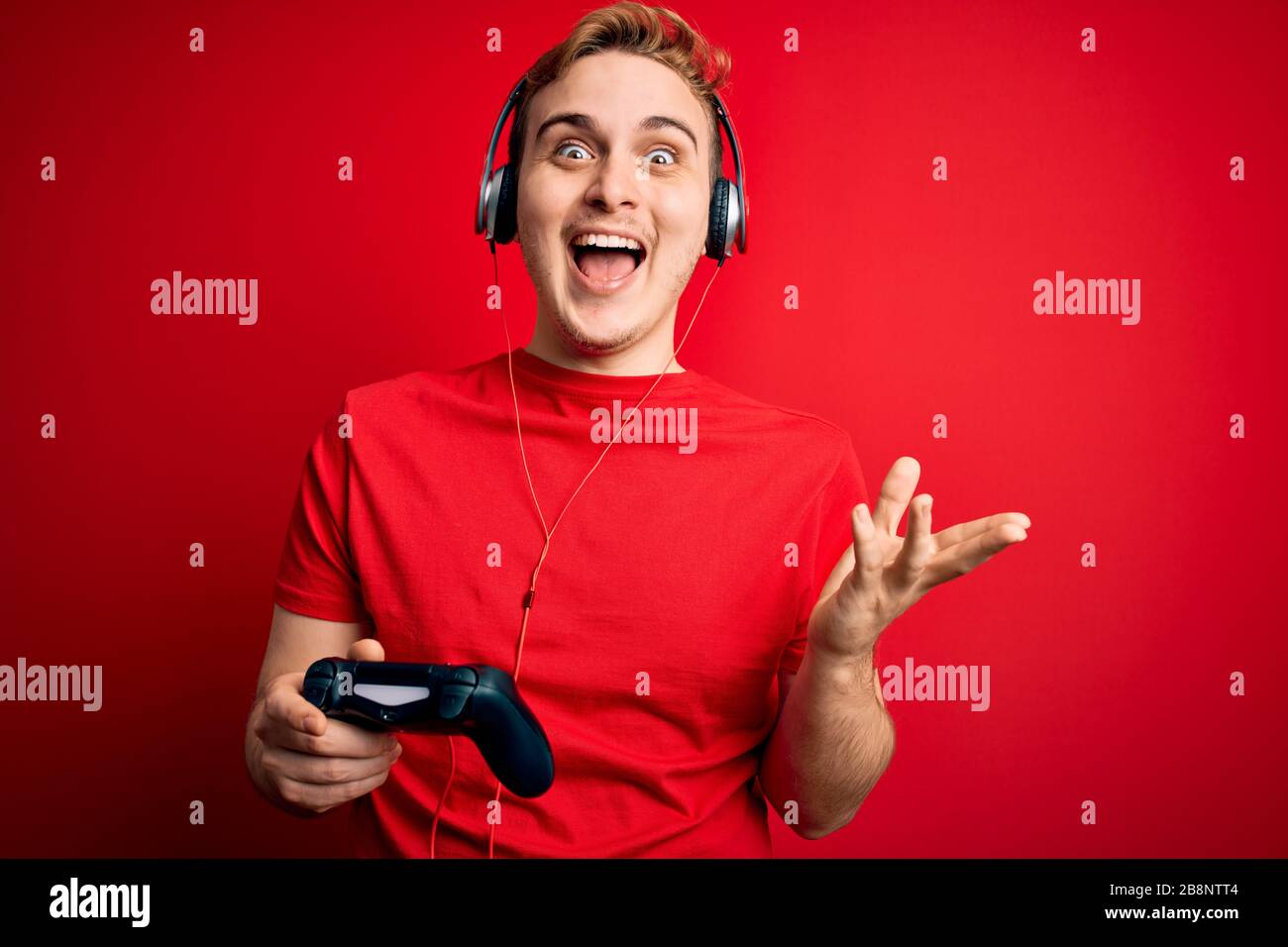 Young handsome redhead gamer man playing video game using headphones ...