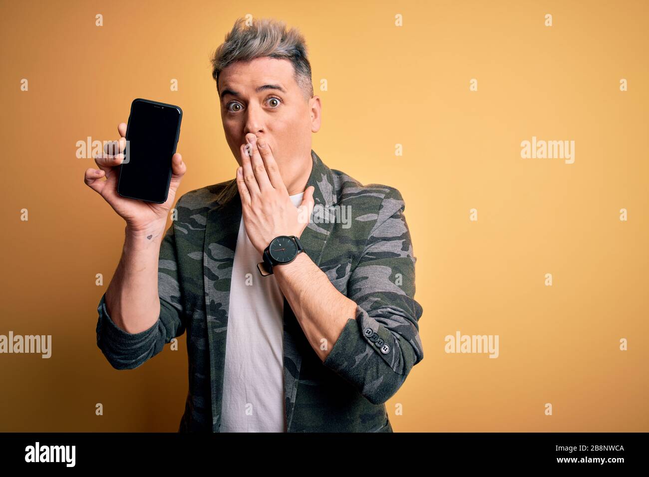 Young modern man showing smartphone blank screen over yellow isolated ...