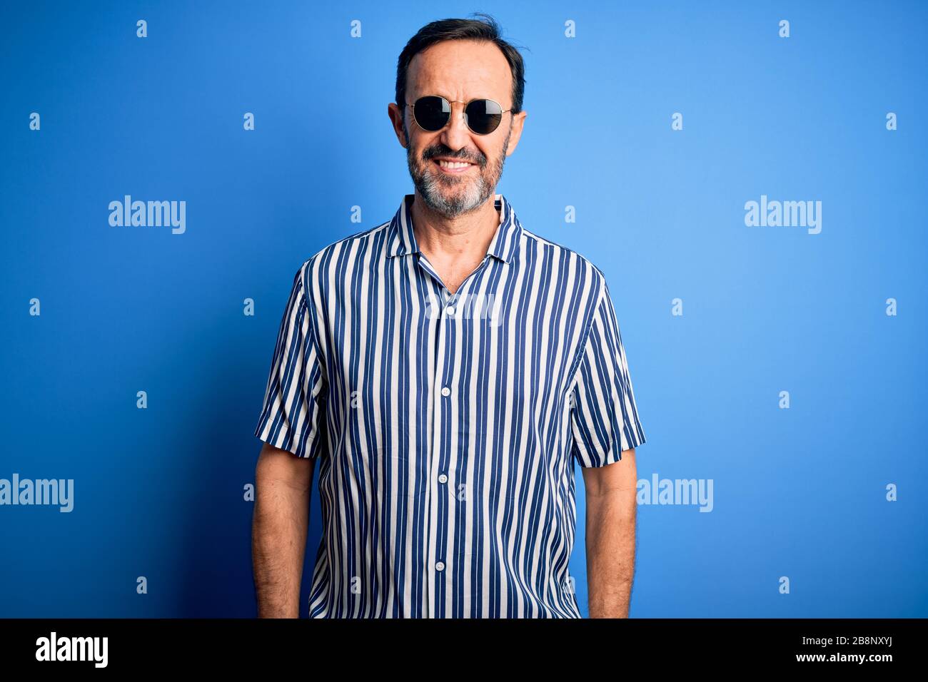 Middle age hoary man wearing striped shirt and sunglasses over isolated ...