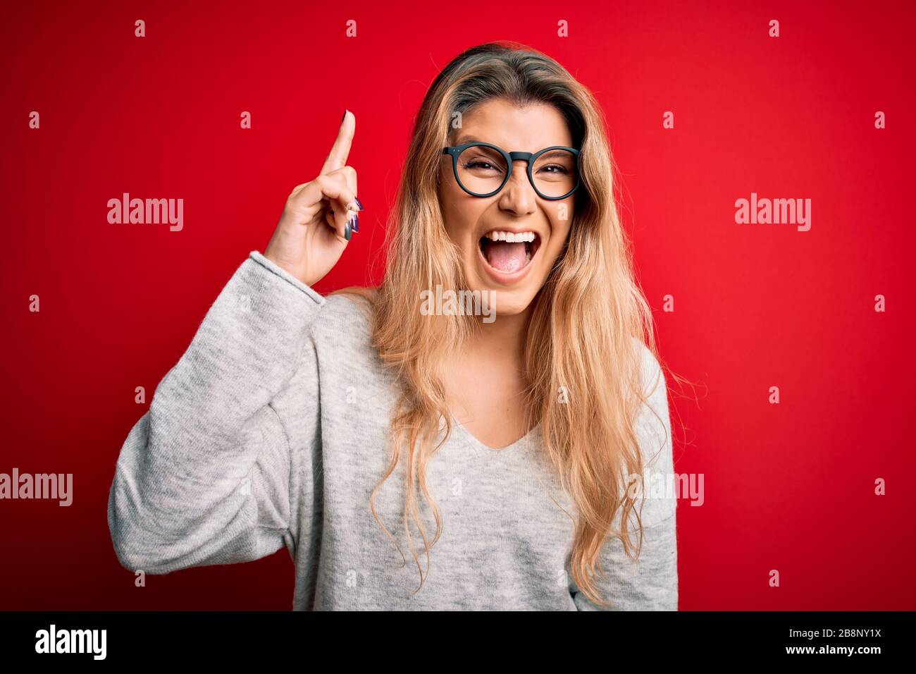 Young Beautiful Blonde Woman Wearing Sweater And Glasses Over Isolated Red Background Pointing