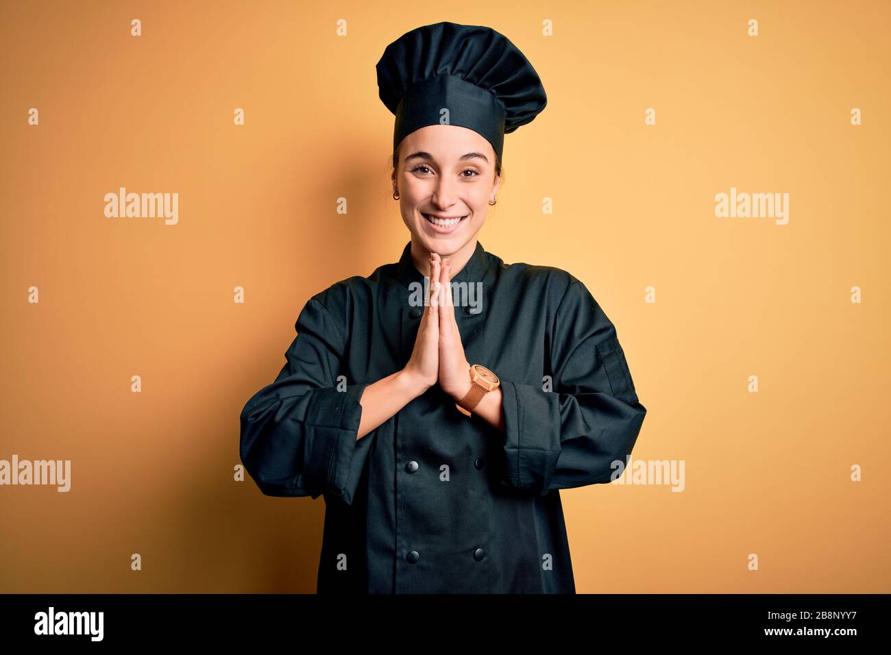 Young beautiful chef woman wearing cooker uniform and hat standing over ...