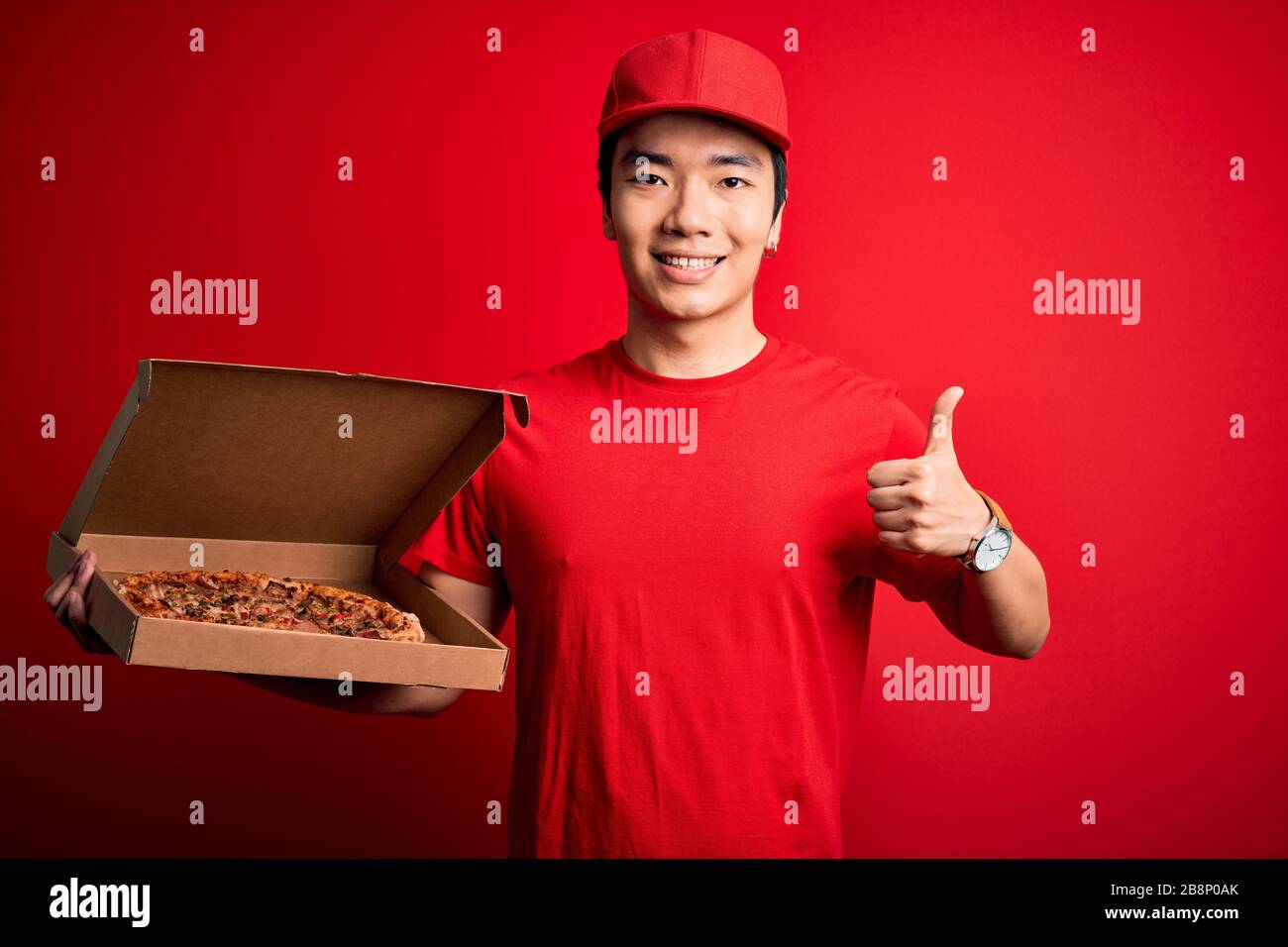 Young handsome chinese delivery man holding deliver box with delicious ...