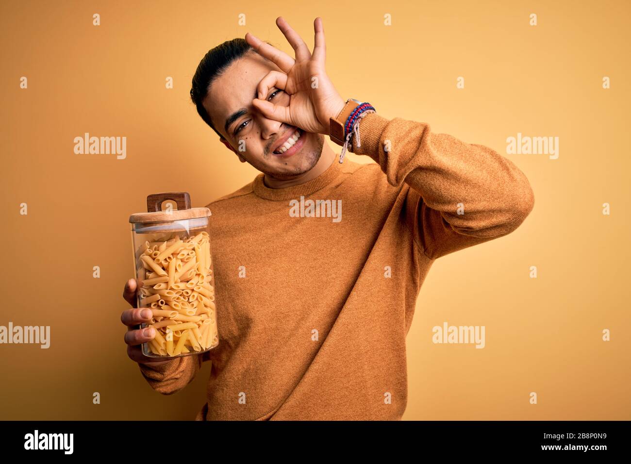 Young brazilian man holding jar with Italian dry pasta macaroni over ...