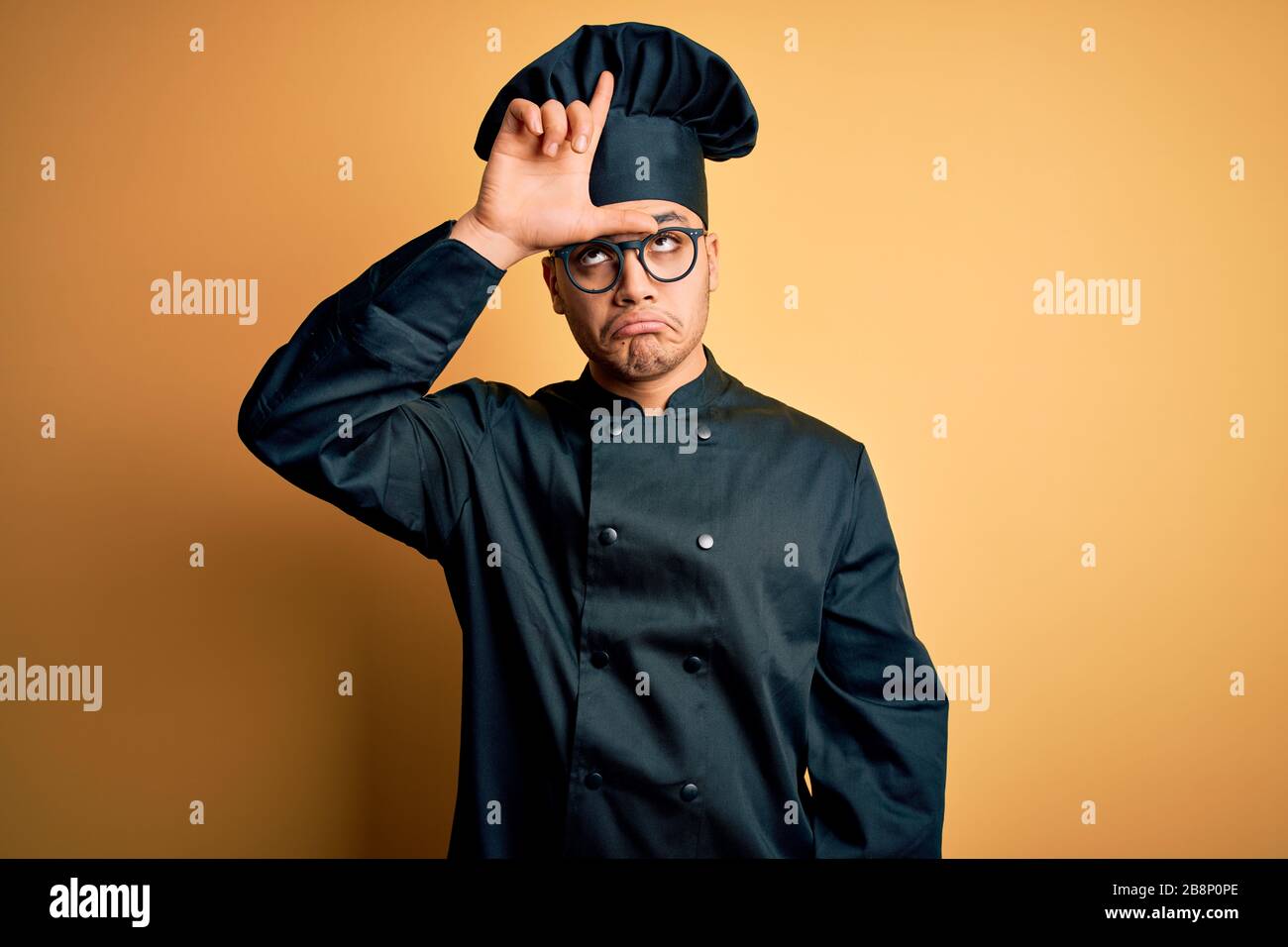 Young brazilian chef man wearing cooker uniform and hat over isolated ...
