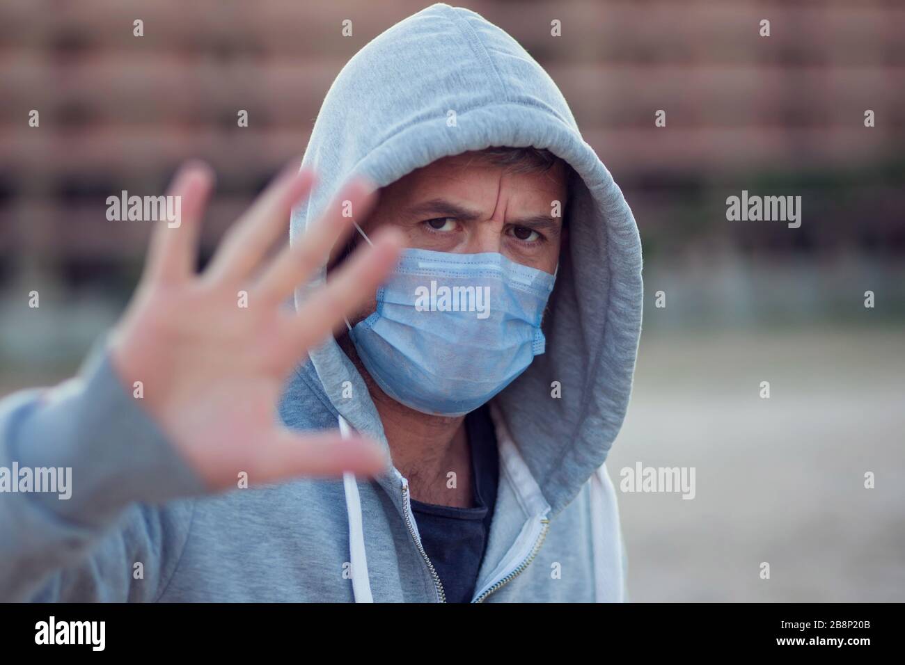A portrait of man with medical face mask showing stop sign with hands ...
