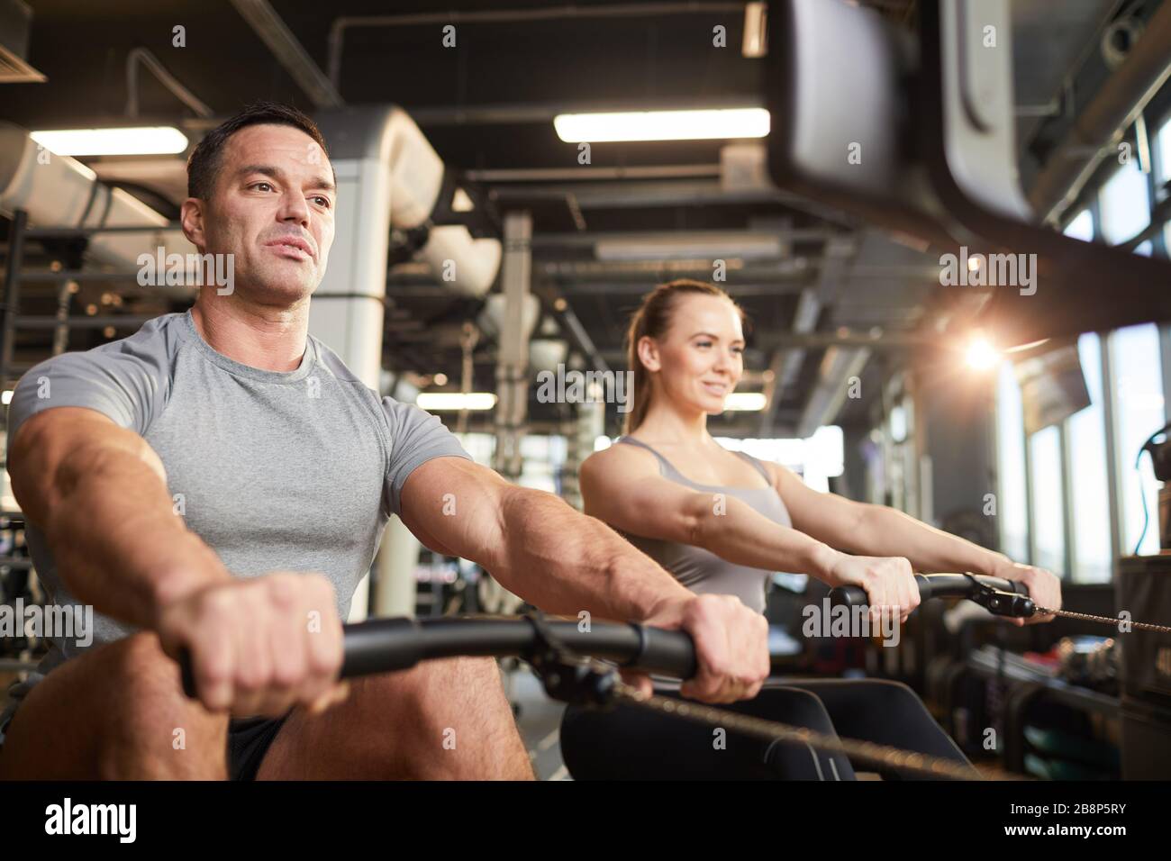Low angle view at muscular man using exercise machine during strength ...