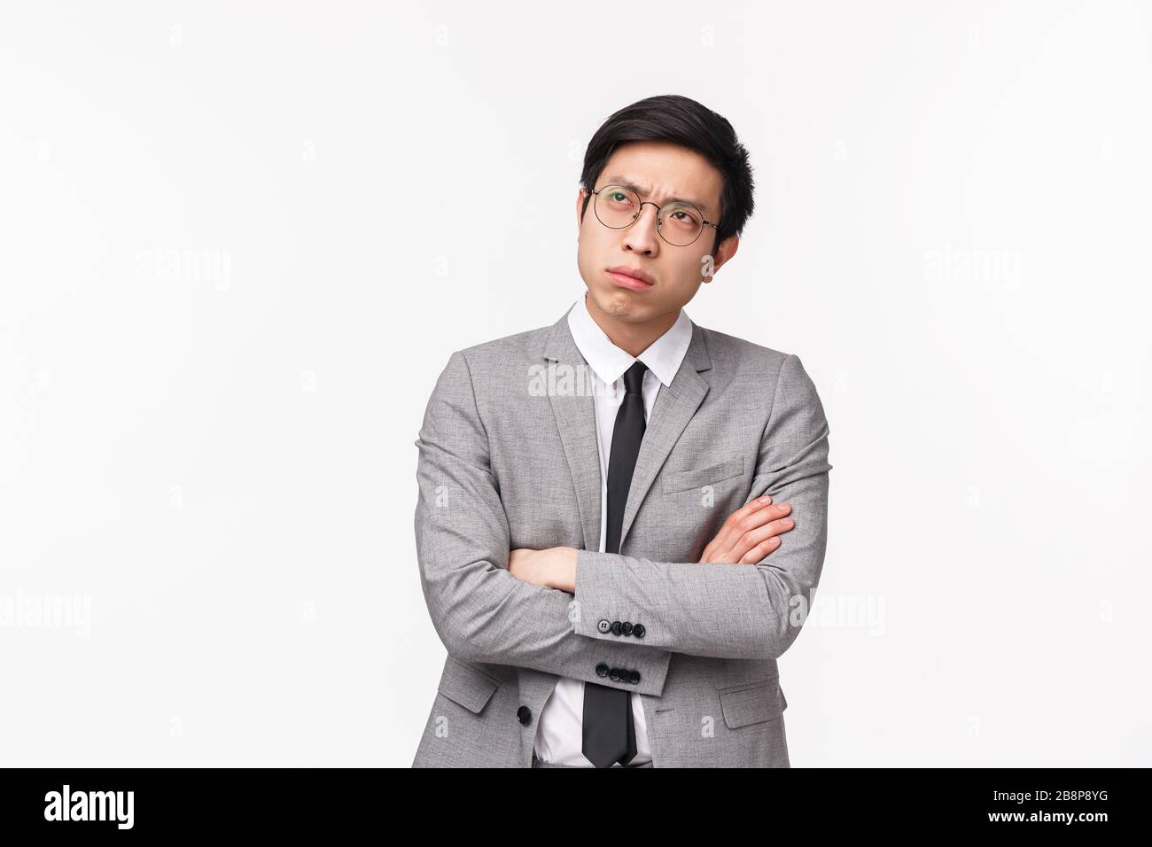 Waist-up portrait of puzzled, serious-looking asian guy in grey suit ...