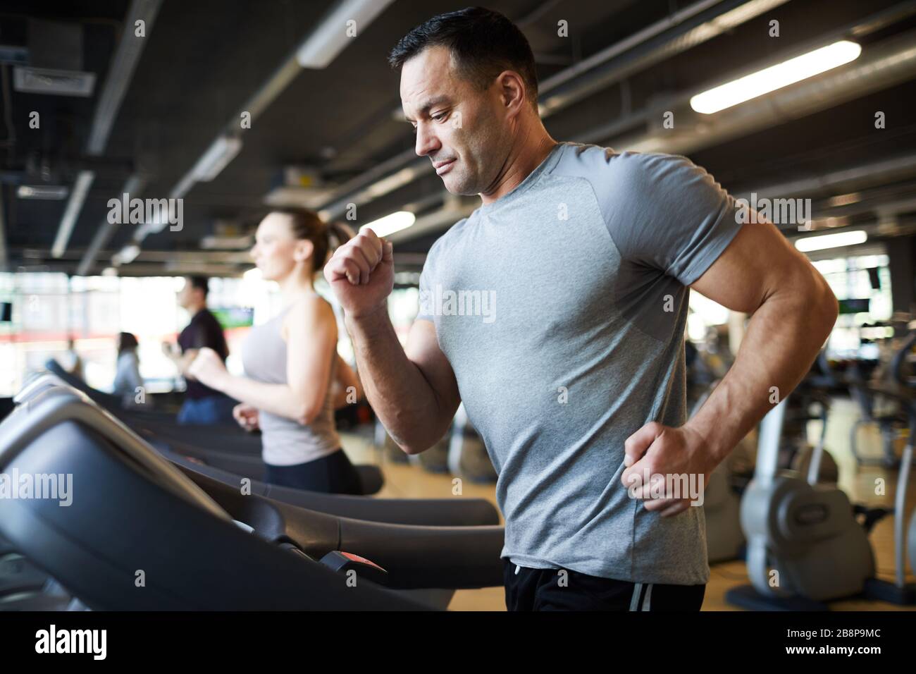 Side view portrait of mature muscular man running on treadmill during ...