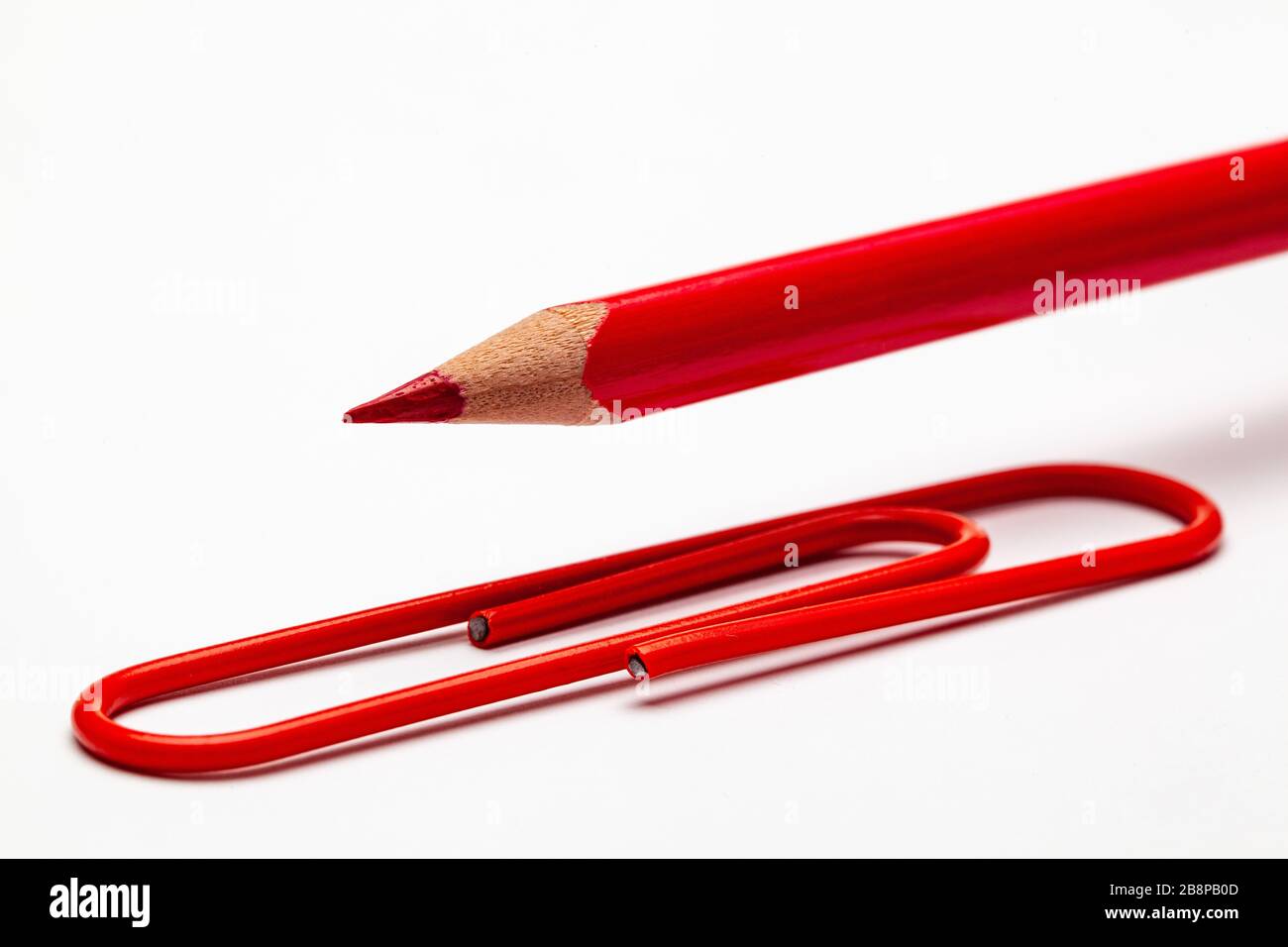 Levitating red color pencil and paperclip on the white office table ...