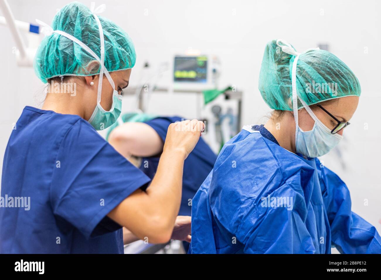 Medical assistant helping a surgeon put on sterile clothes in an ...