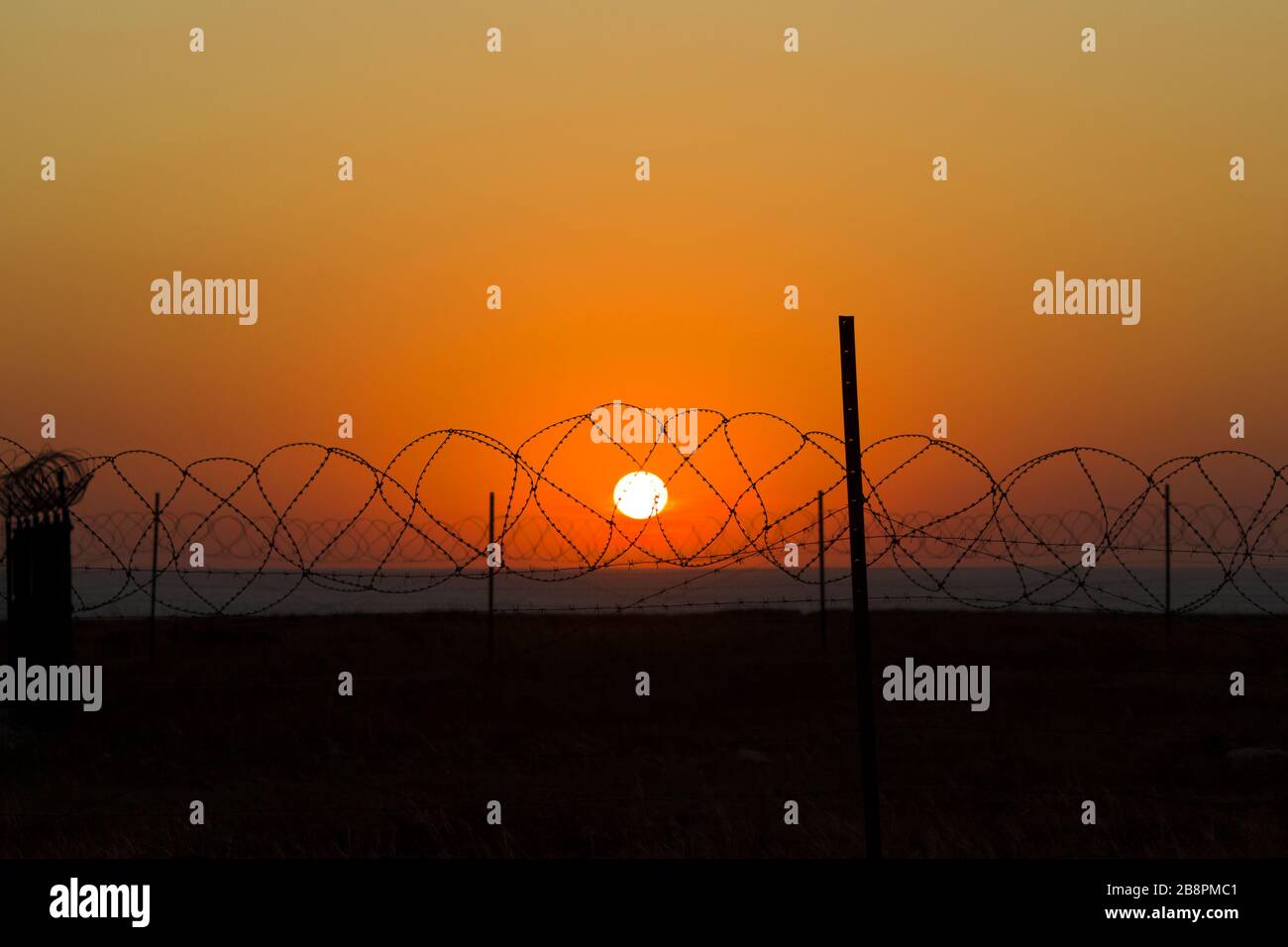 silhouette of barbed wire against the setting sun. freedom concept ...
