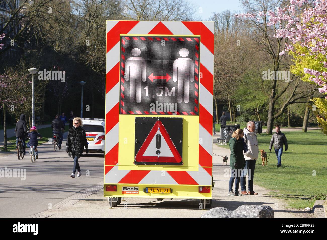 People walking pass a sign urging people to practice social distancing ...