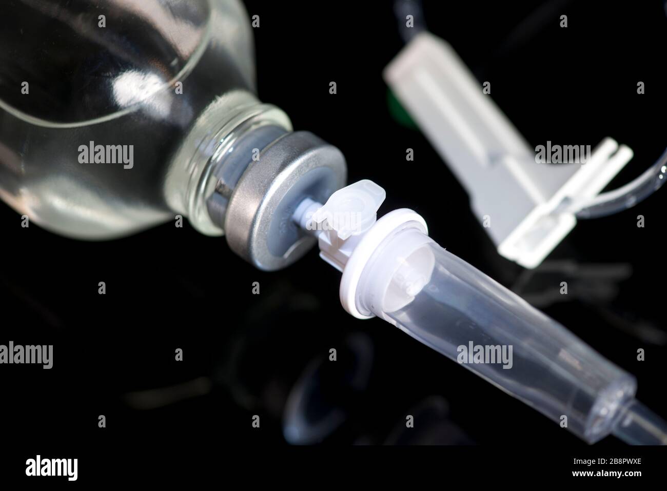 Glass IV bottle with IV drip chamber and IV flow adjustor on dark ...