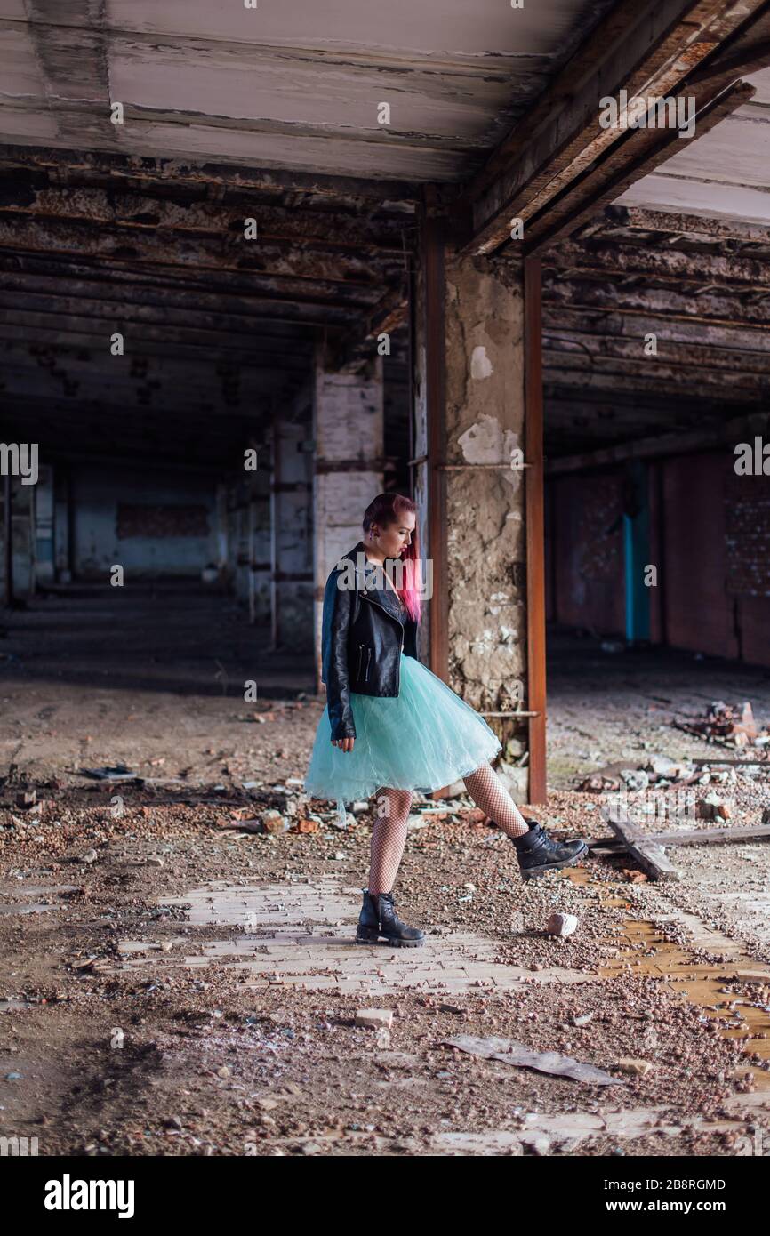 Portrait of a young girl with pink hair standing inside of collapsed ...