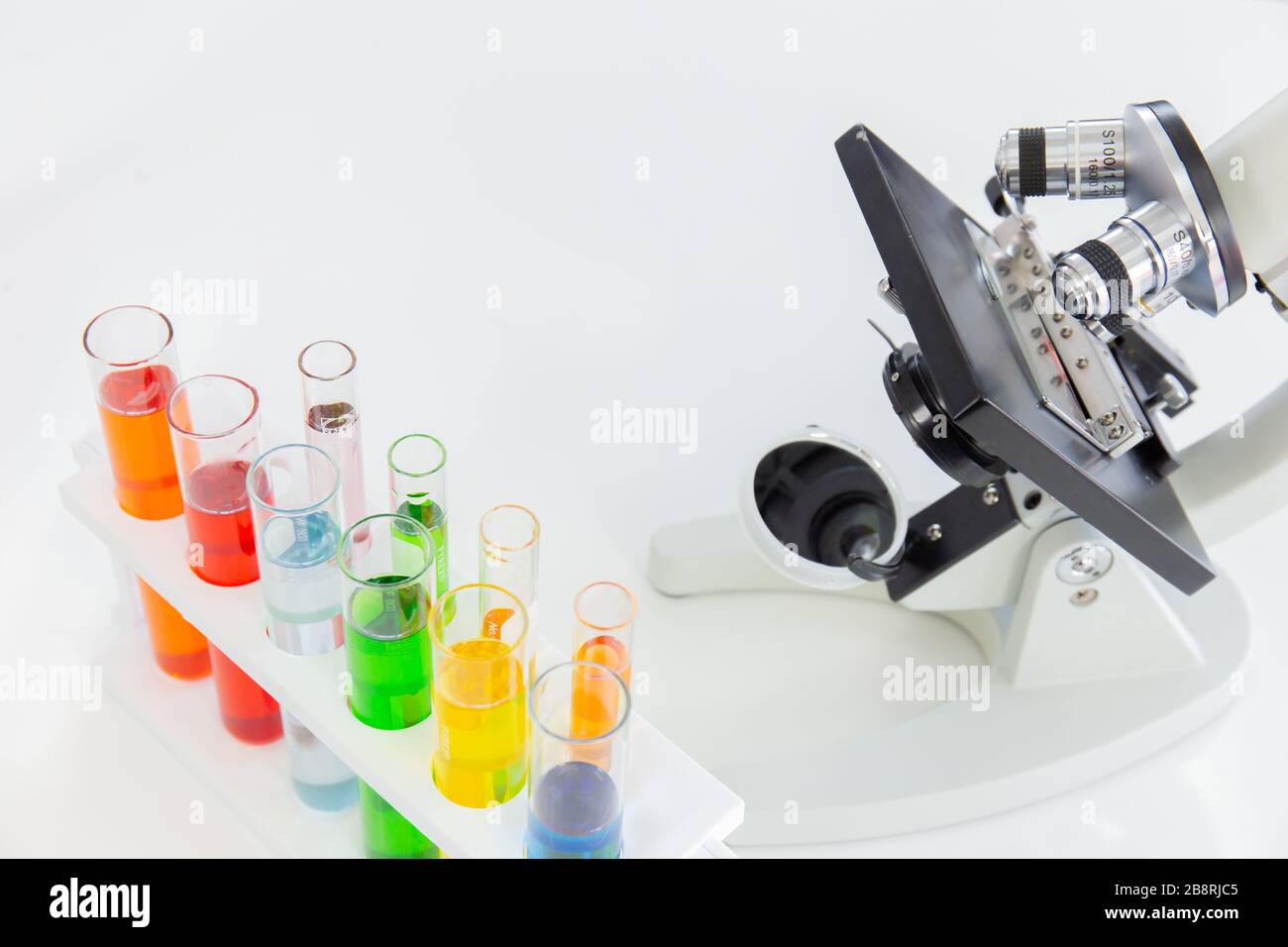 Test tubes in a stand and a microscope on a white table Stock Photo - Alamy