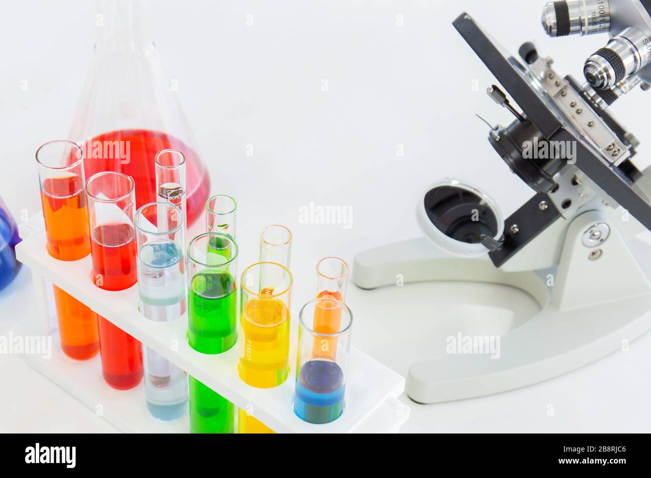 Test tubes in a stand and a microscope on a white table Stock Photo - Alamy