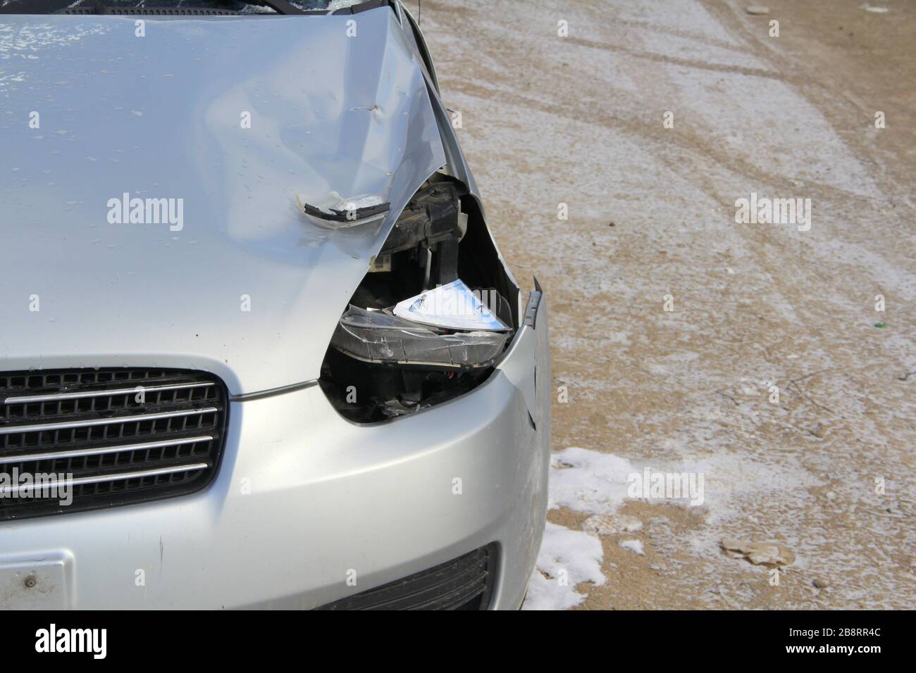 A broken silver car after an accident on the road. Broken headlight ...