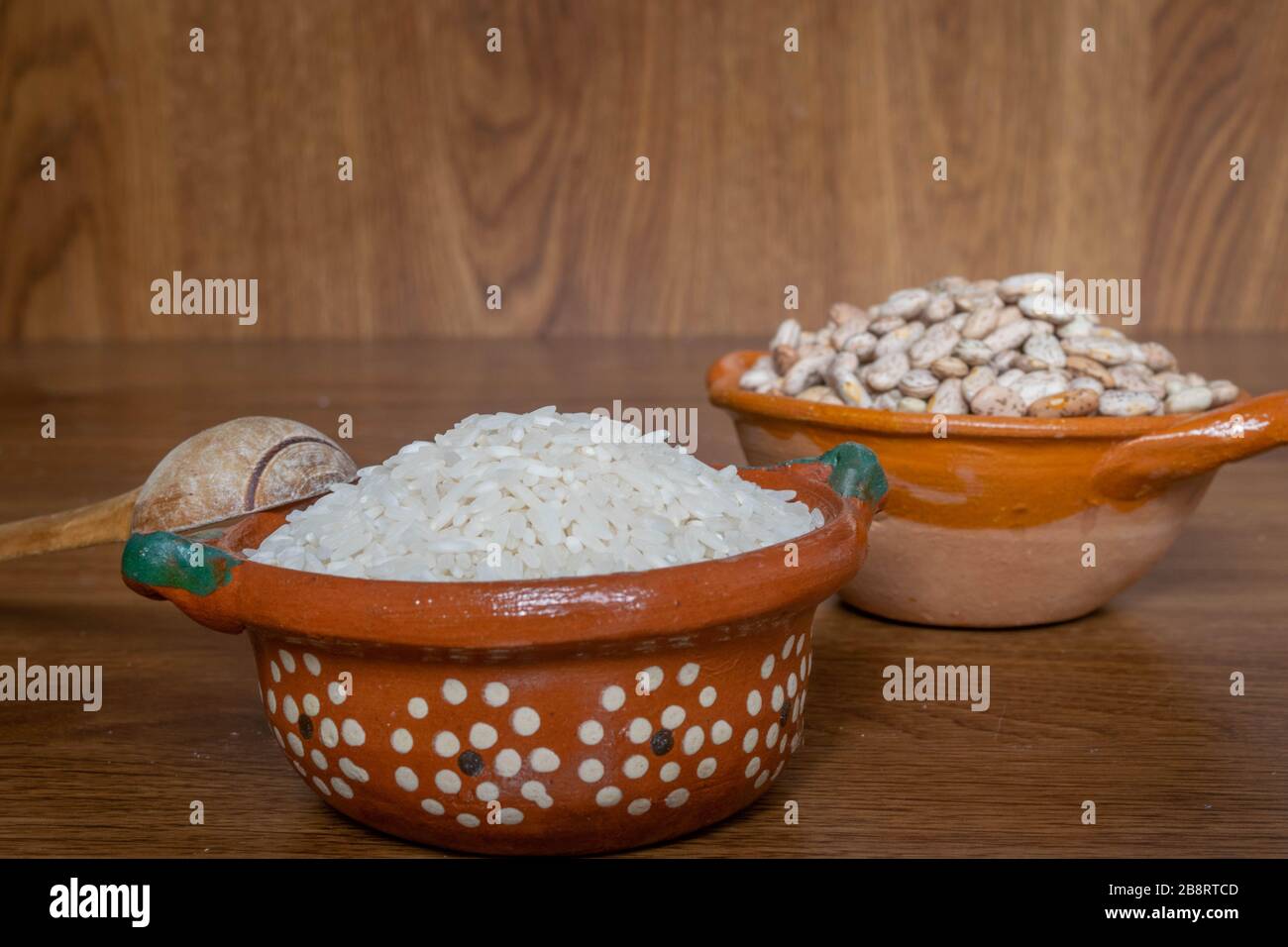 Mexican style clay containers with rice grains and beans on wooden ...