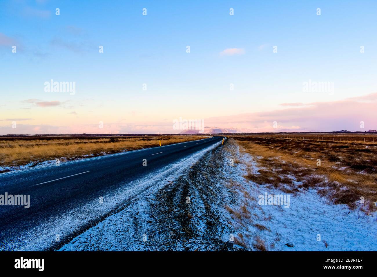 A road with grassy fields on both sides Stock Photo - Alamy