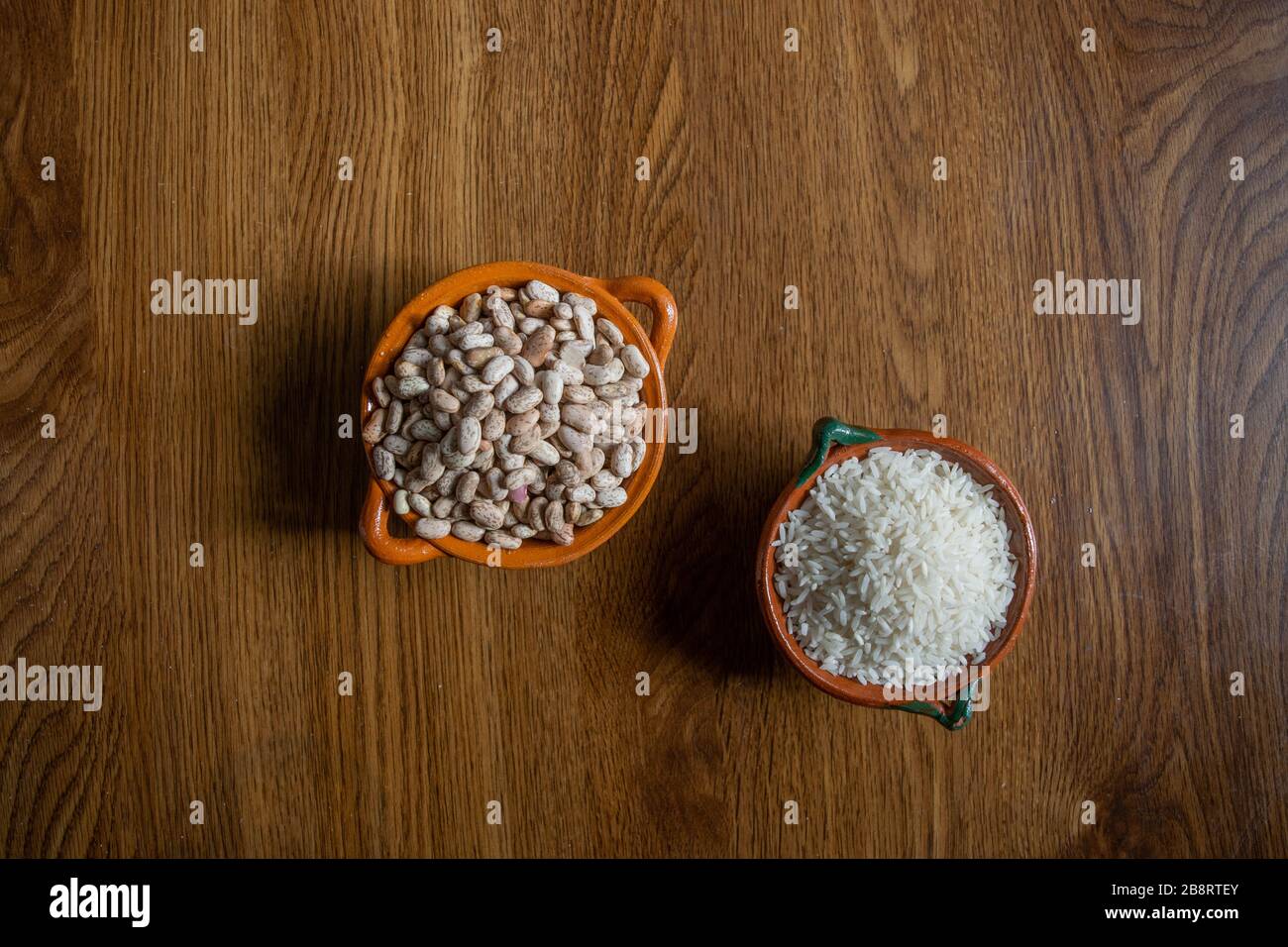 top view of Mexican style clay containers with rice grains and beans on ...