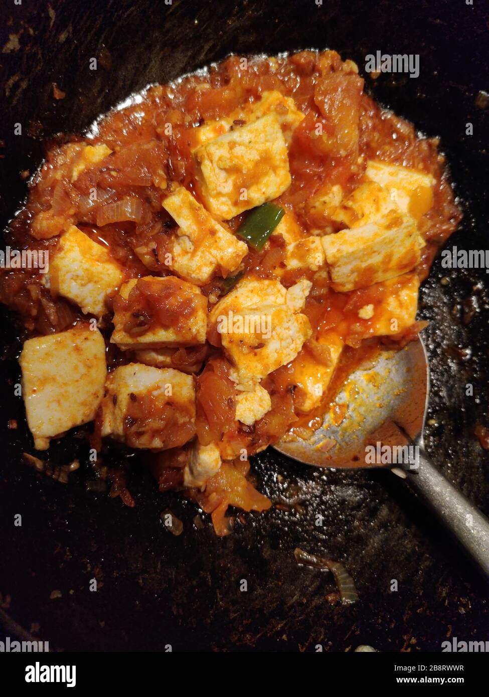 Preparation of Kadai paneer, panner cubes are stirred slowly in black ...
