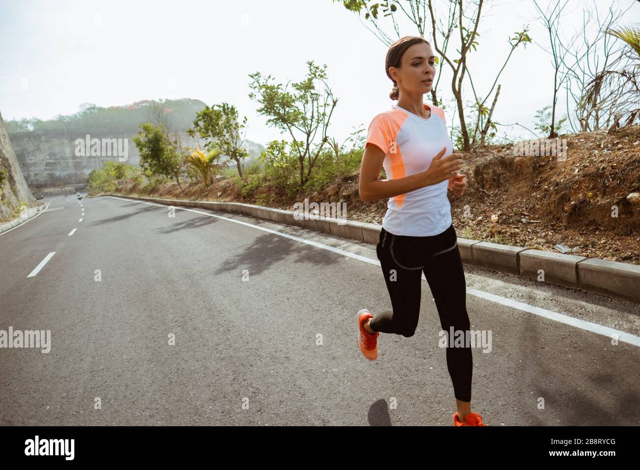 sport woman running on sideroad. fit woman jogging on empty road Stock ...