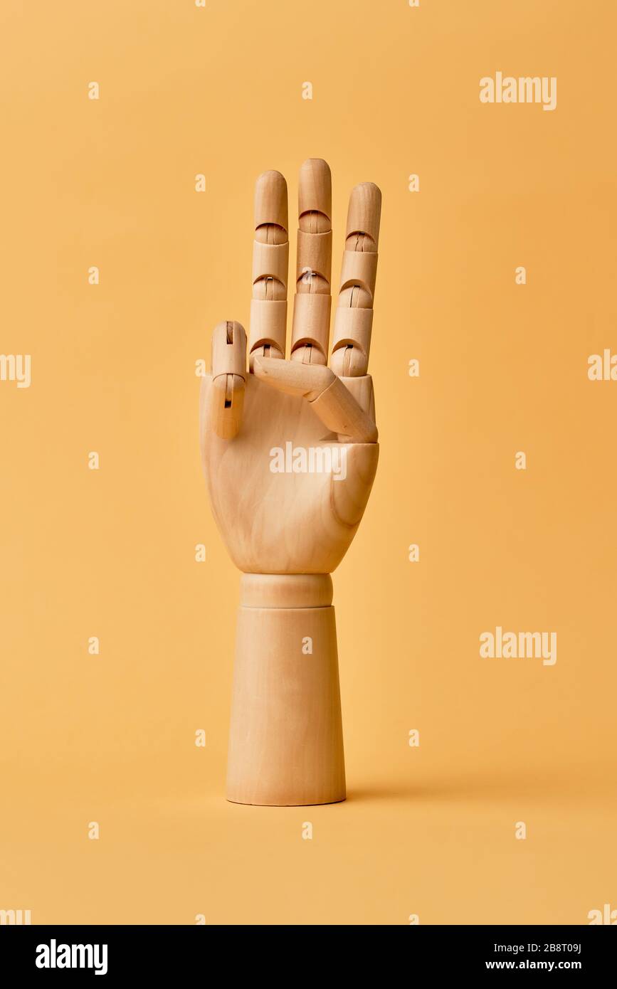 Wooden human hand with three fingers raised up isolated on orange ...
