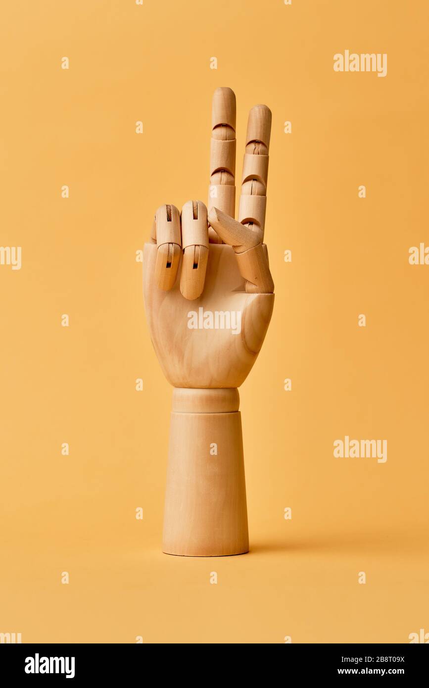 Wooden human hand with two fingers raised up isolated on orange ...