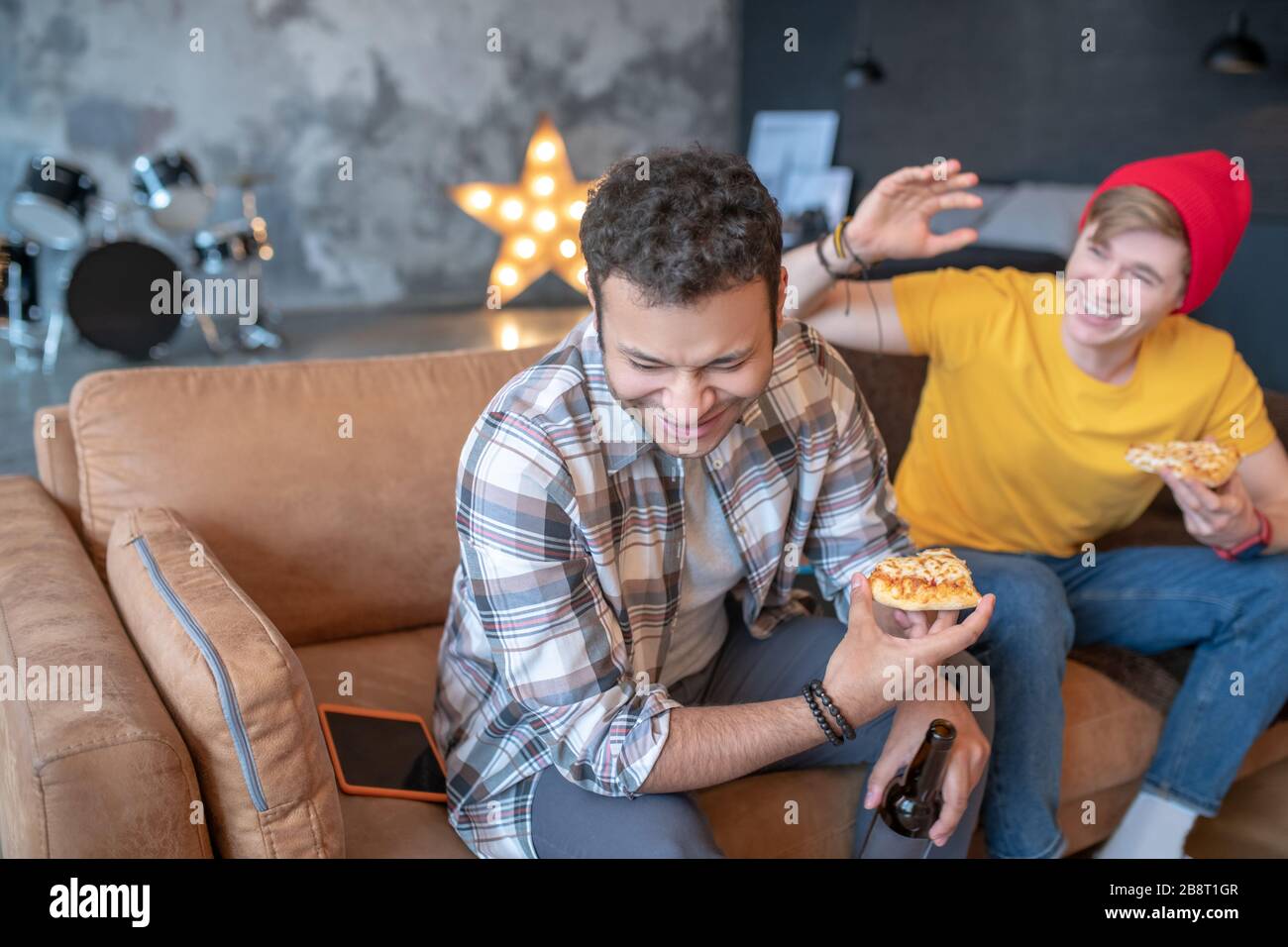 Two friends eating pizza on sofa hi-res stock photography and images ...